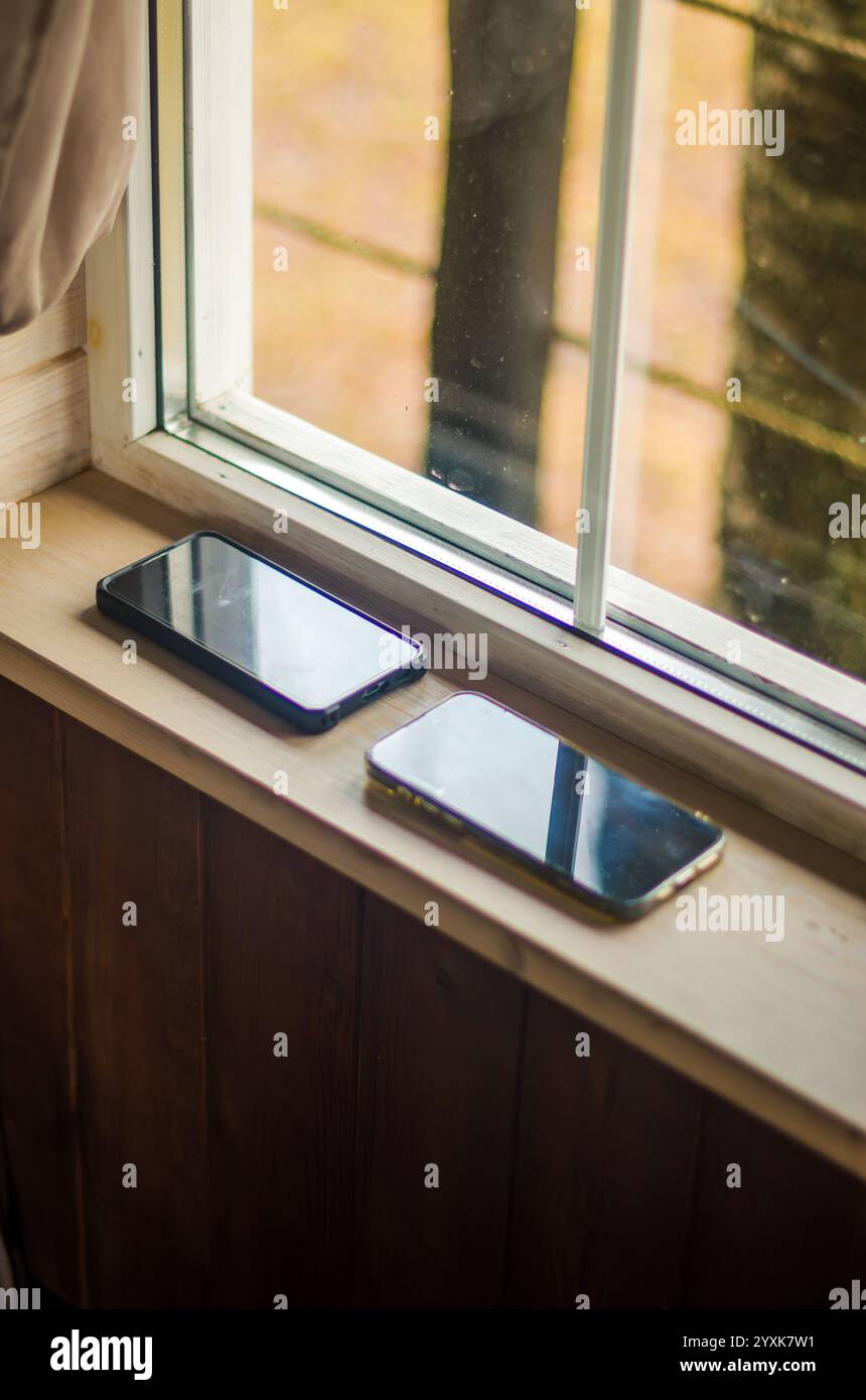Two turned off phones on wooden windowsill near the window . High ...