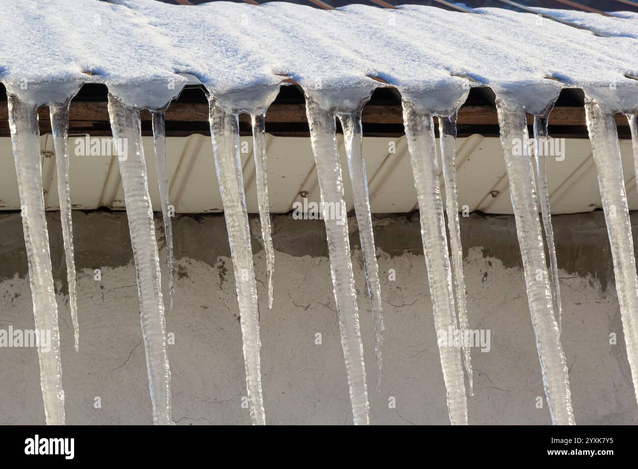 Sharp icicles and melted snow hanging from eaves of roof. Beautiful ...