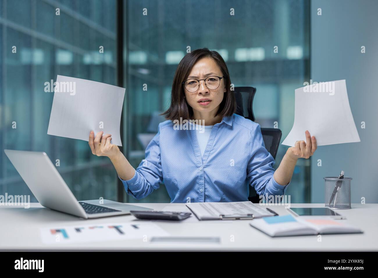Asian businesswoman expressing frustration holding documents at her ...