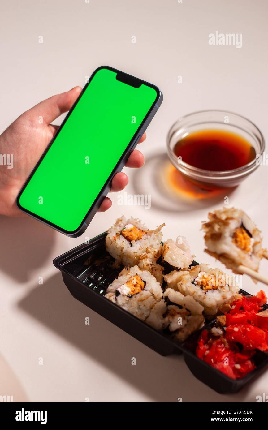 Female using smartphone while eating sushi rolls at home. Smartphone ...
