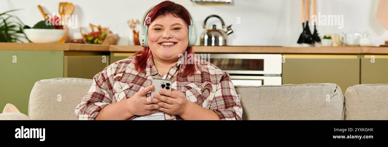 Bright and cheerful plus size woman relaxes on a couch while using her ...