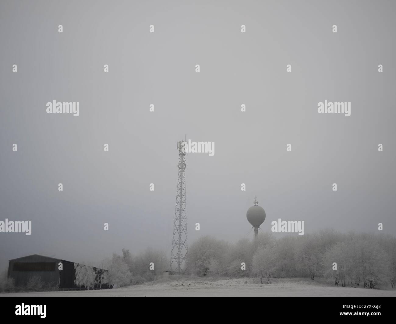 Telecommunication tower and water tower emerging from frozen landscape ...