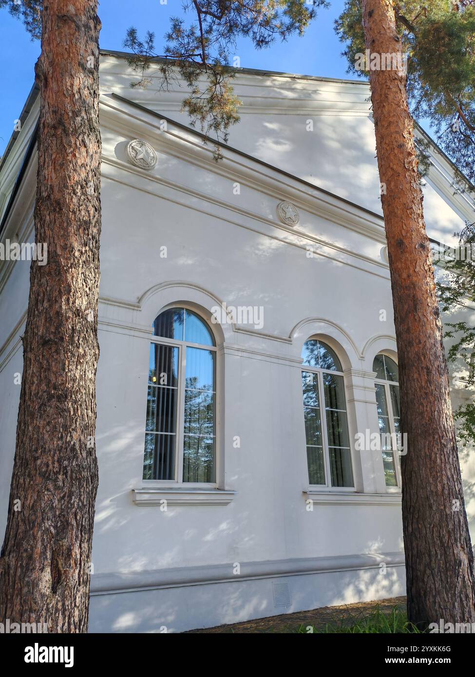 A white historic structure with symmetrical arched windows and ...