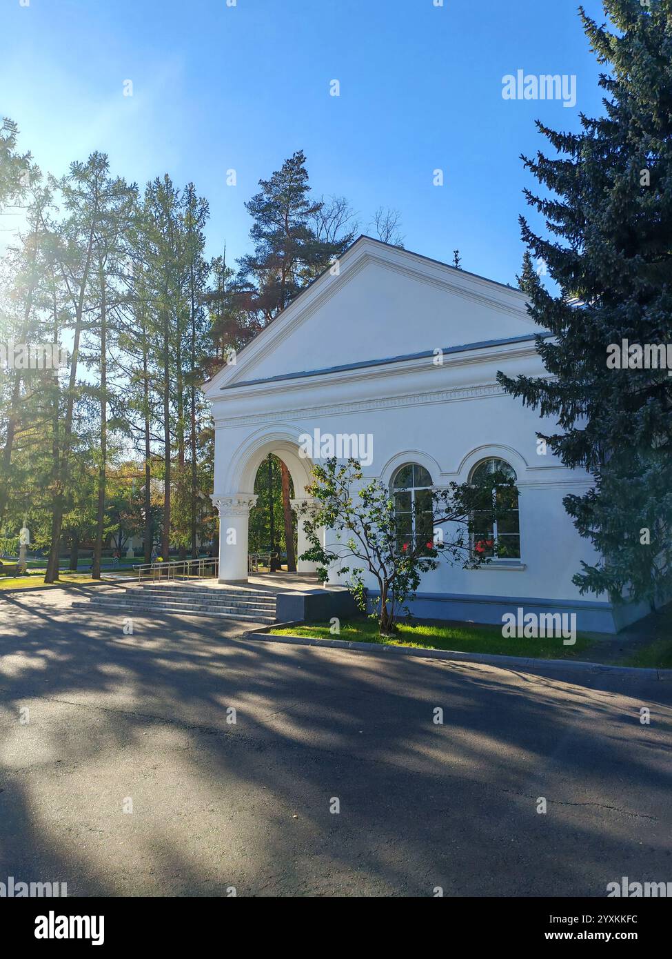 A white neoclassical structure with arched windows, framed by sunlight ...