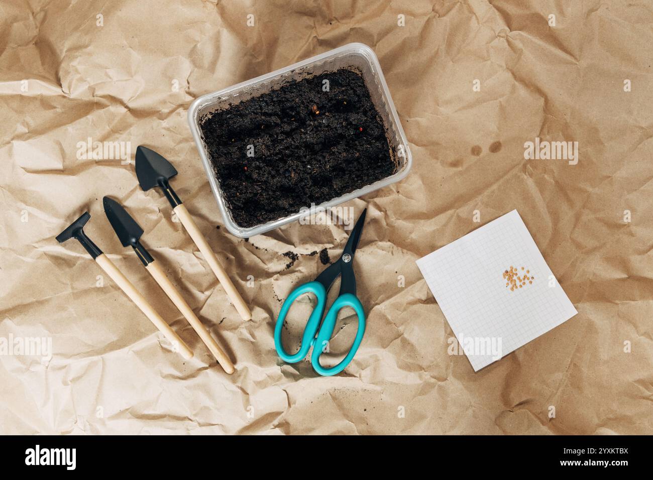Kraft paper background, fertile soil and garden tools on top, top view ...