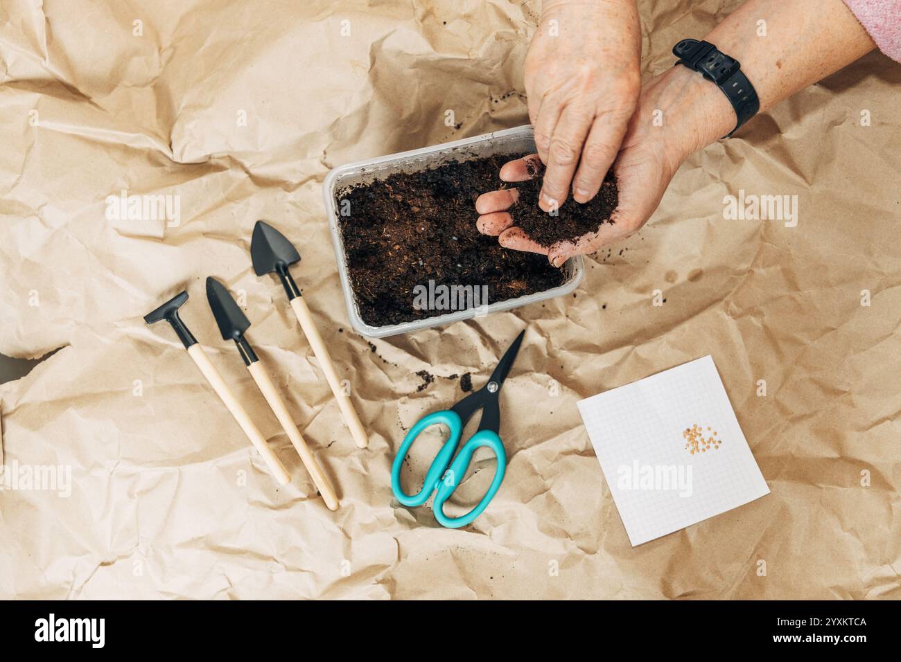 Kraft paper background, fertile soil and garden tools, top view. Hands ...