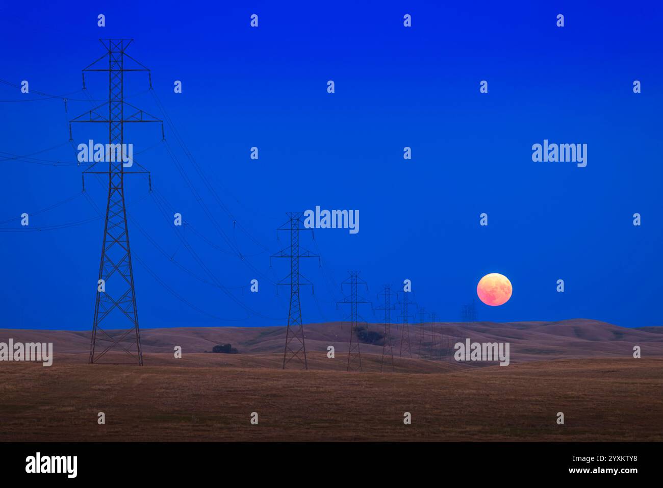 Full Moon rising at the end of a long line of high tension towers in ...
