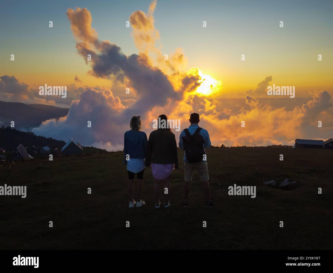 Three friends are enjoying a breathtaking sunset over a vast sea of ...