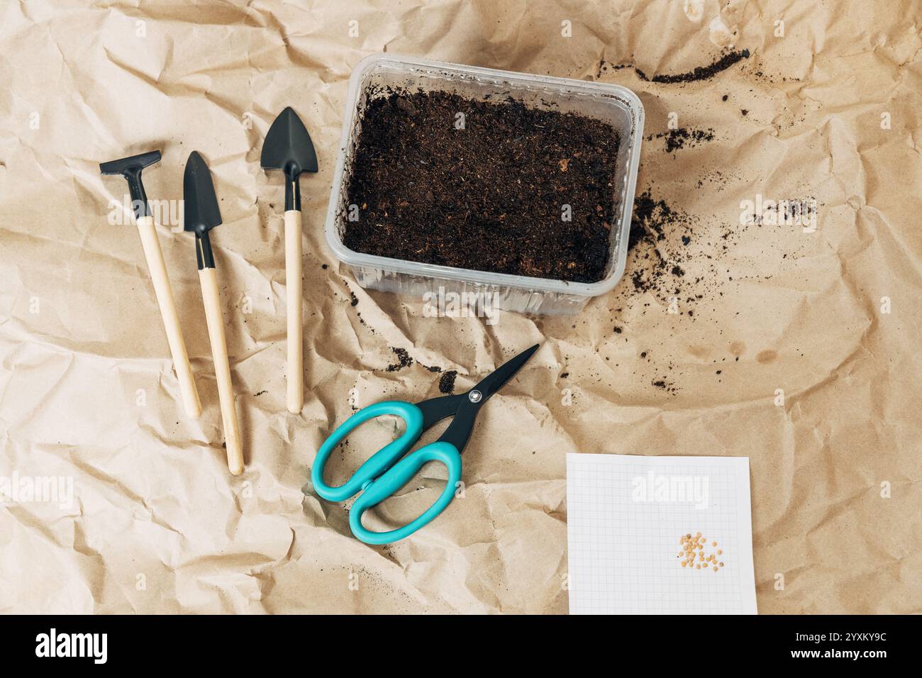 Kraft paper background, fertile soil and garden tools on top, top view ...