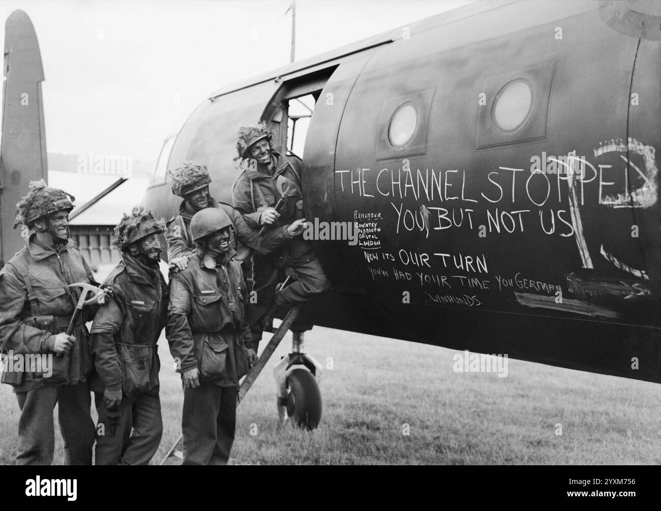 Airborne troops admire the graffiti chalked on the side of their glider ...