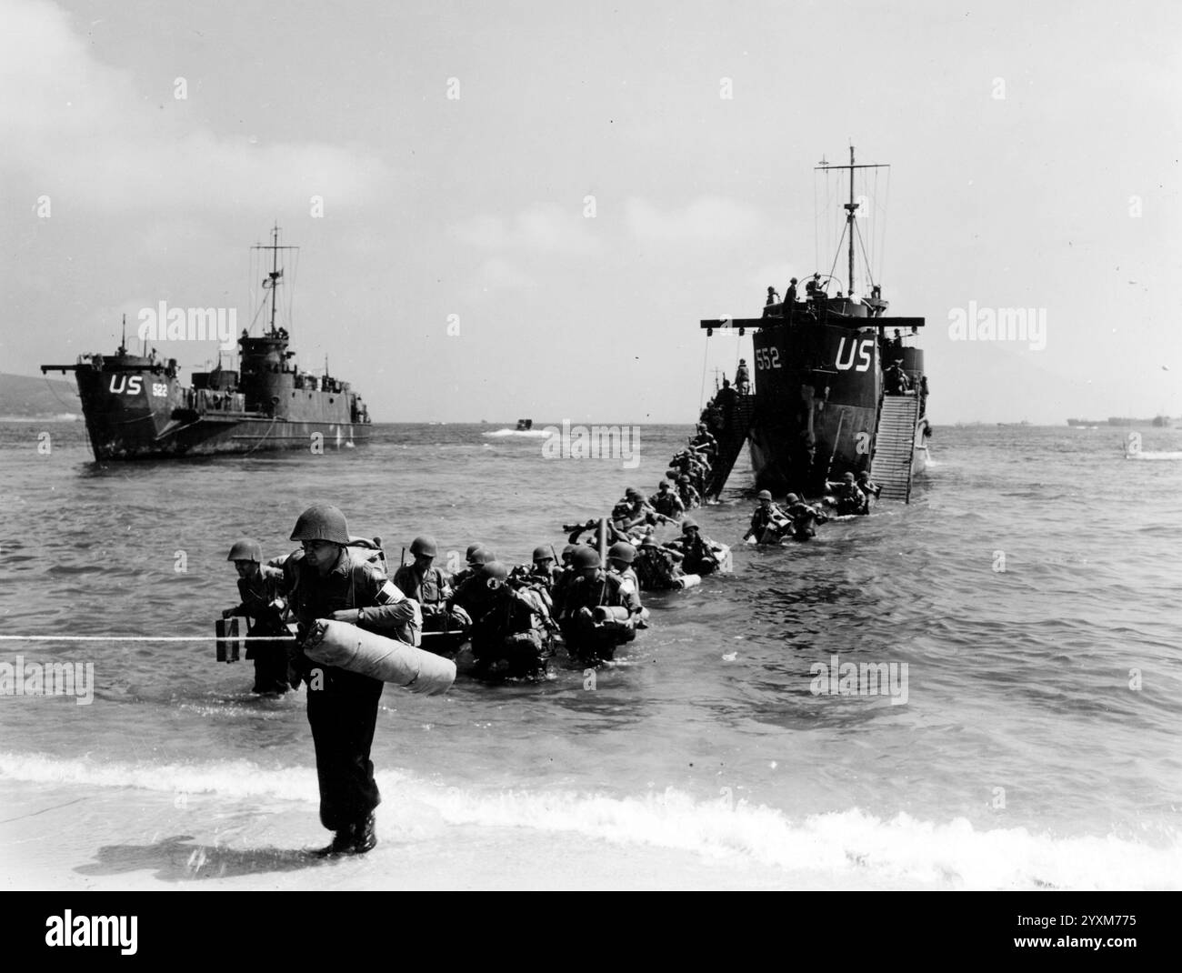 American infantrymen debark from an LCI and plod through chest-high ...