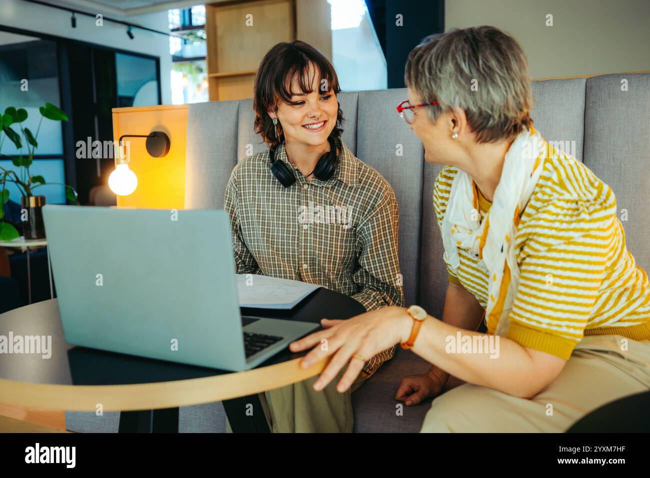 Female teacher assisting a student with their work in a contemporary ...