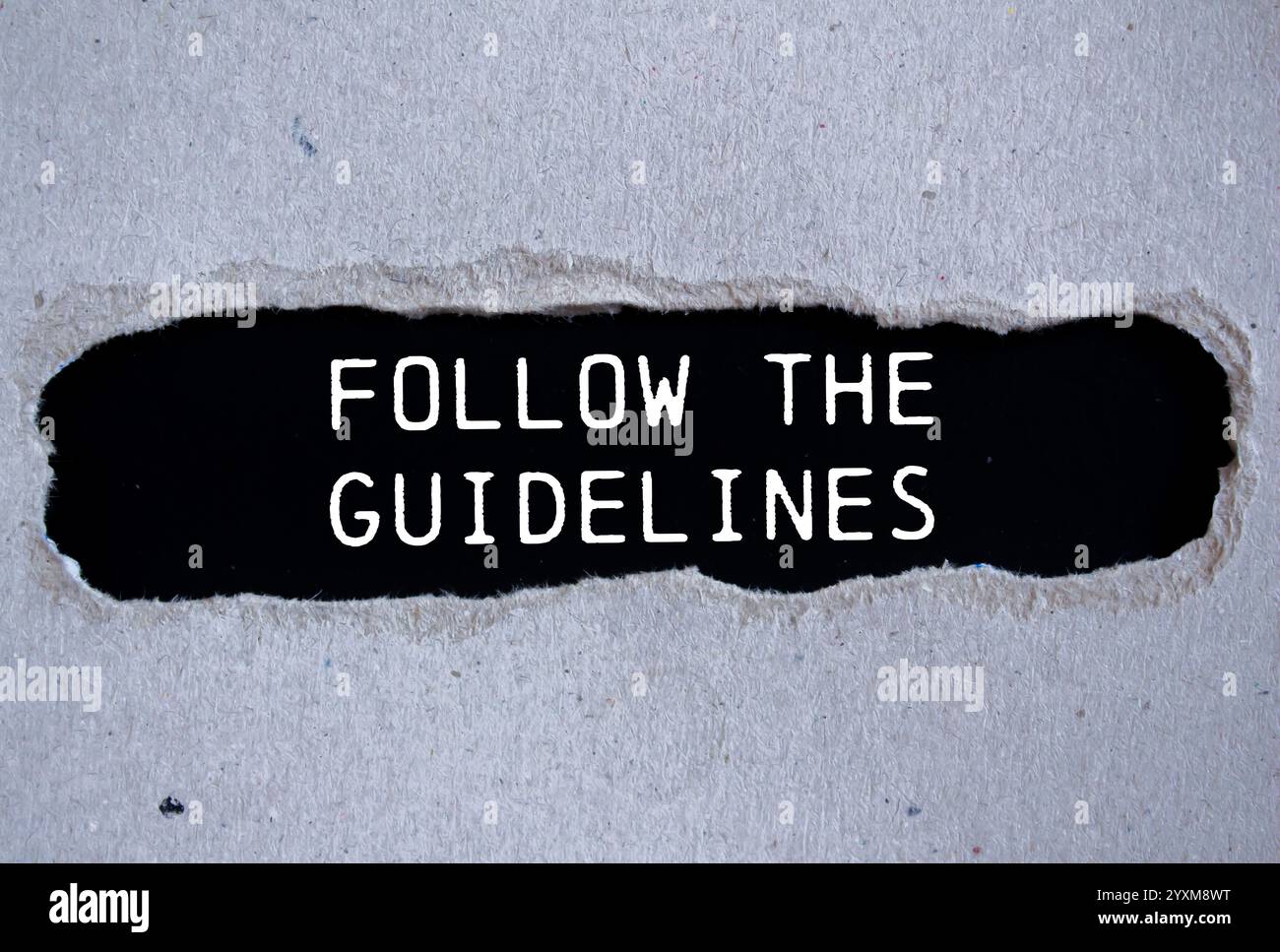 Follow the guidelines message written on ripped torn gray paper with black background ...