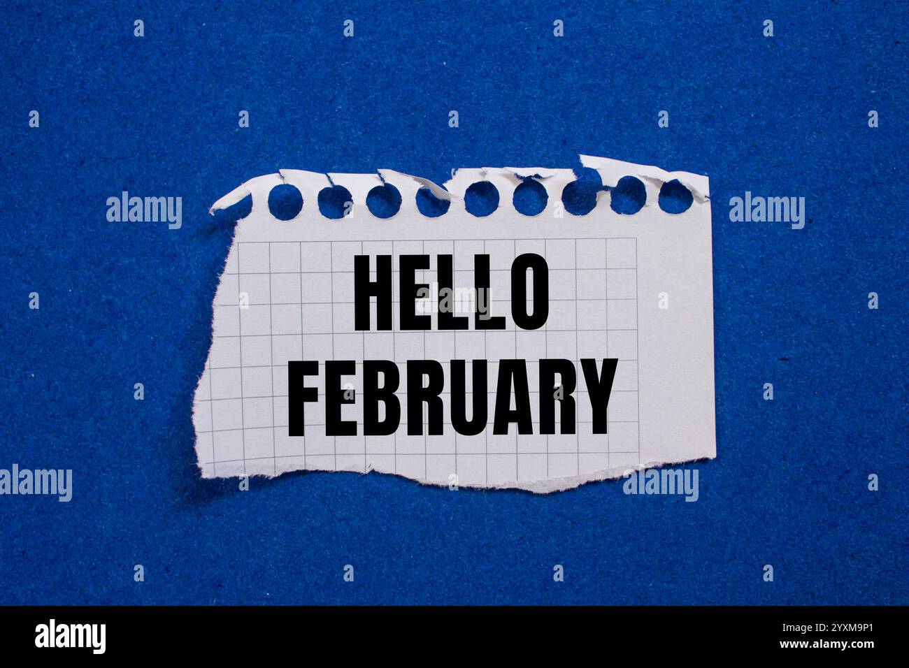Hello february message written on ripped torn paper piece with blue ...