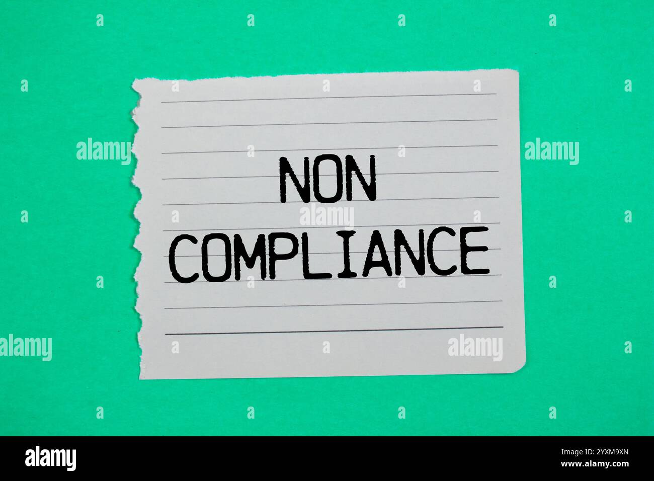 Non compliance message written on ripped torn paper piece with green background. Conceptual non ...