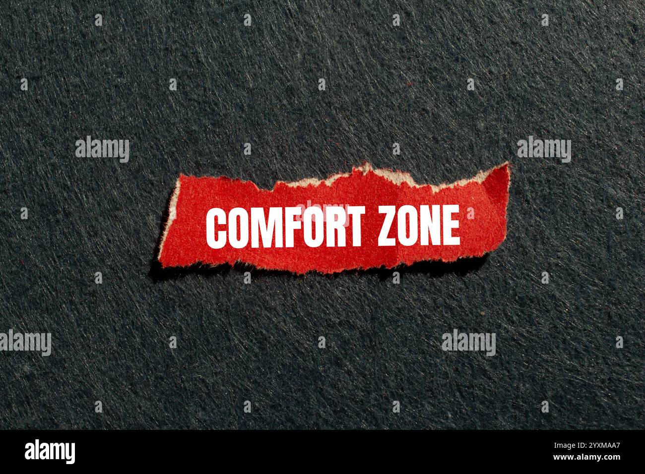Comfort zone message written on ripped torn red paper piece with gray background. Conceptual ...