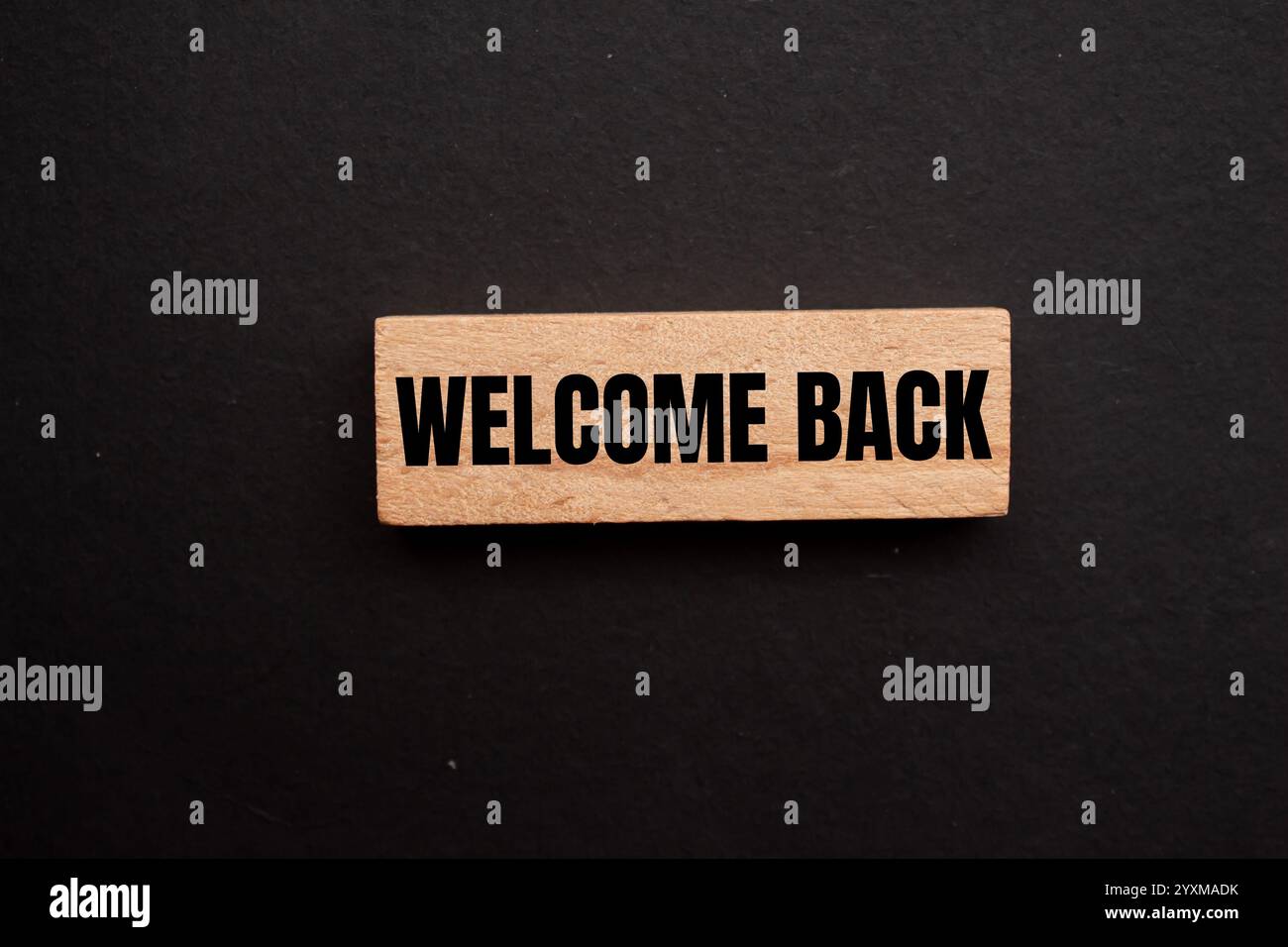 Welcome back message written on wooden block with black background ...