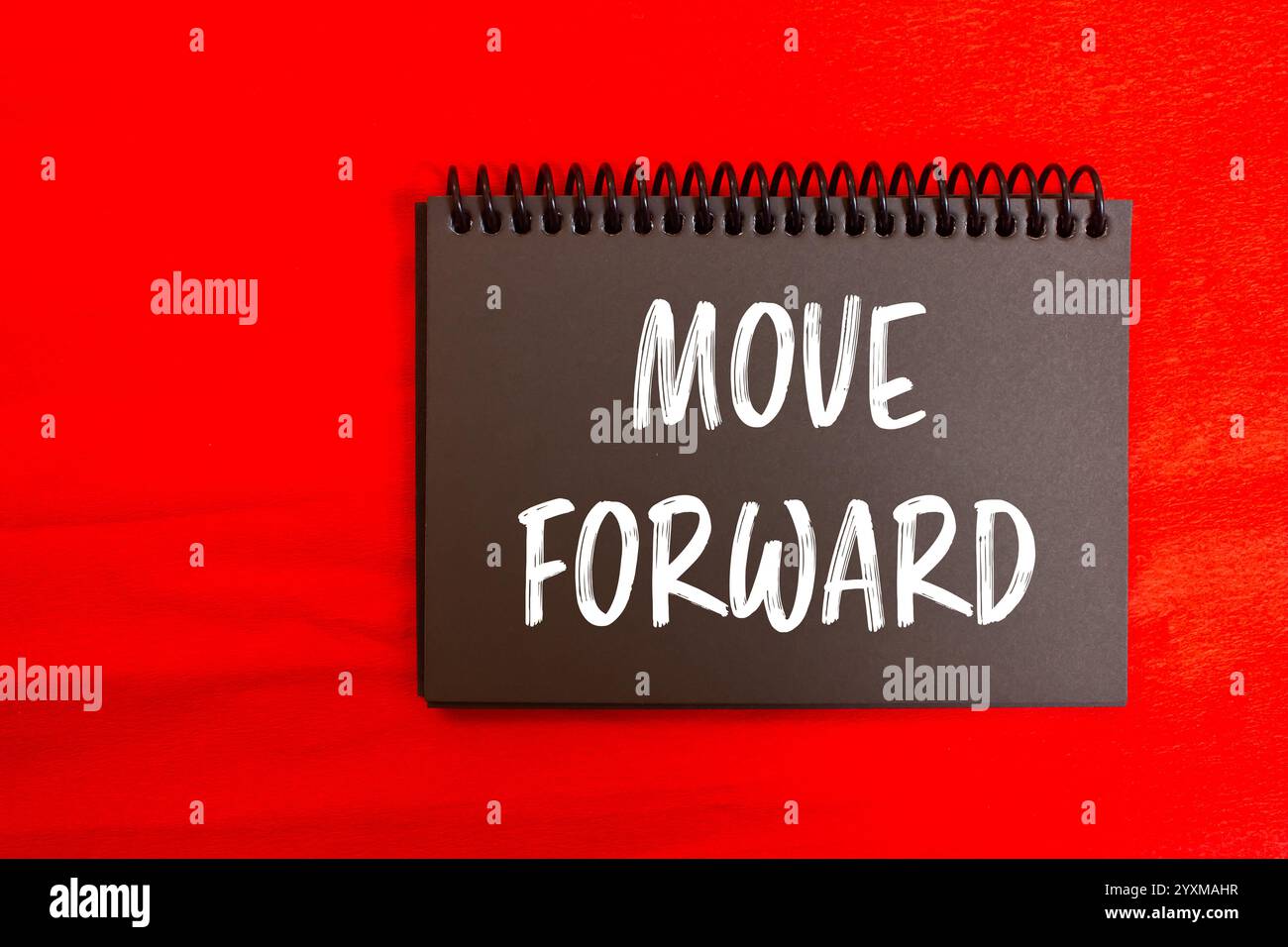Move forward message written on black notebook page with red background. Conceptual move forward ...