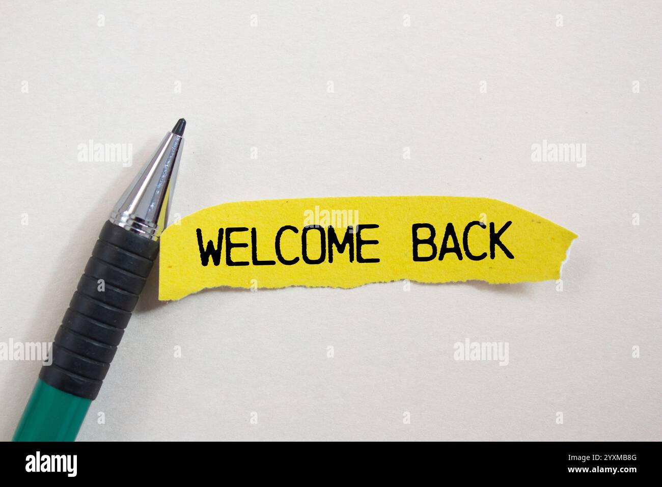 Welcome back message written on ripped torn yellow paper piece and a ...