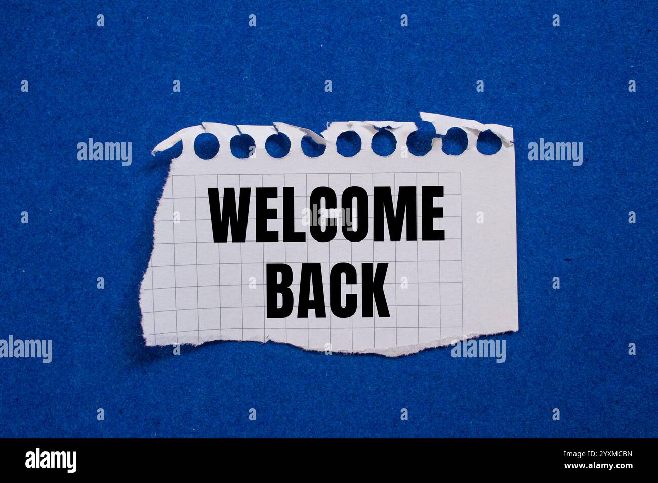 Welcome back message written on ripped torn paper piece with blue ...