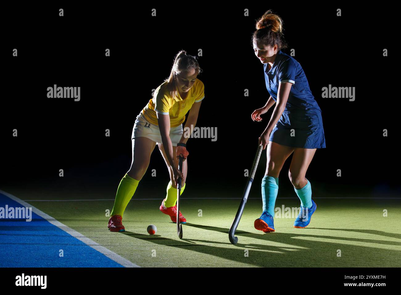 Two field hockey players compete in an intense match under contrast ...