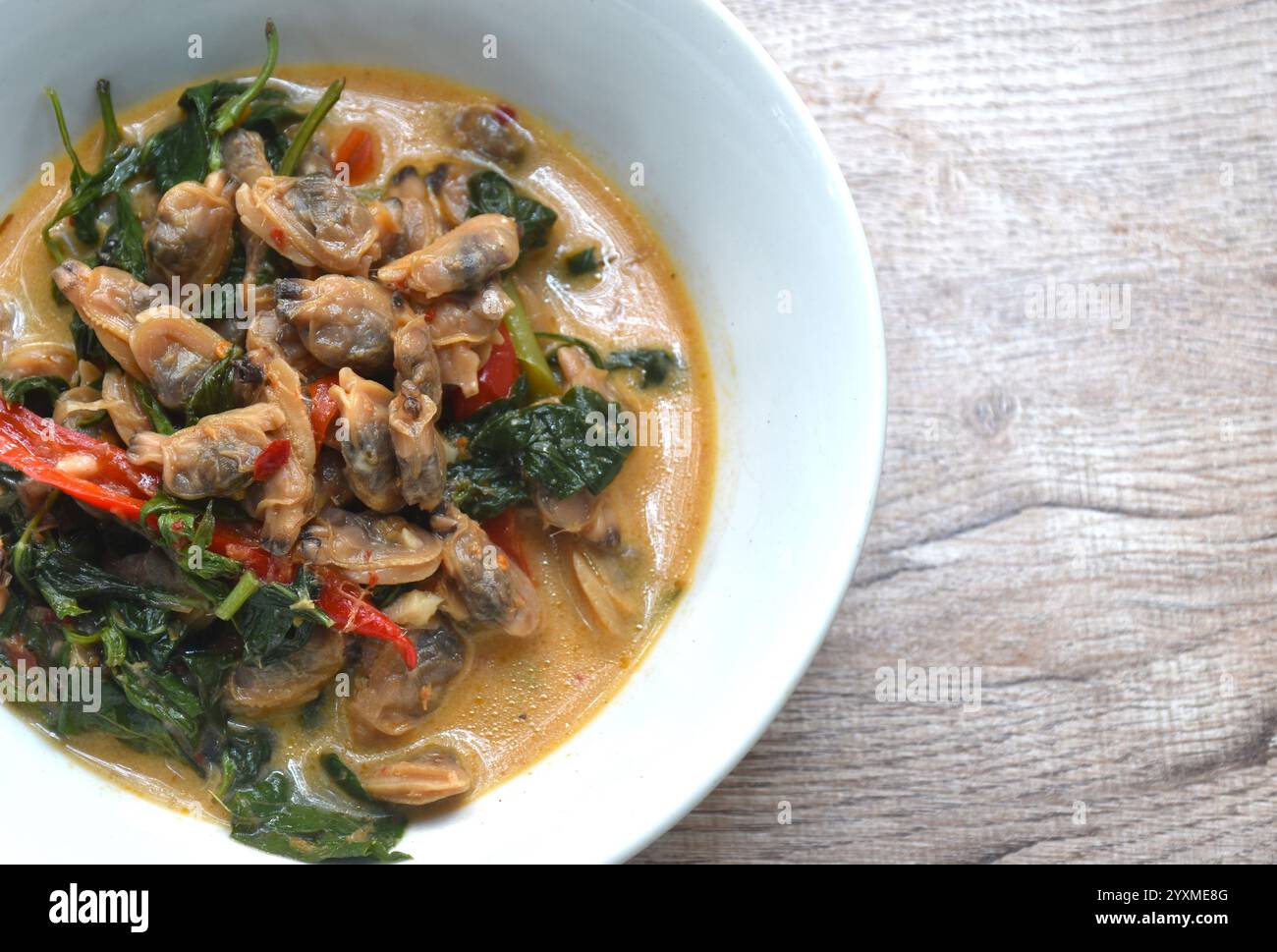 spicy boiled clam with basil in curry and coconut milk soup on bowl ...