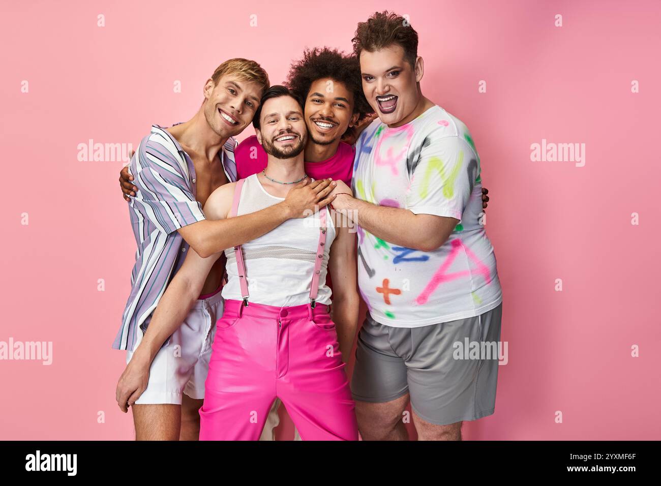 Four friends embrace joyfully against a pink backdrop, celebrating ...