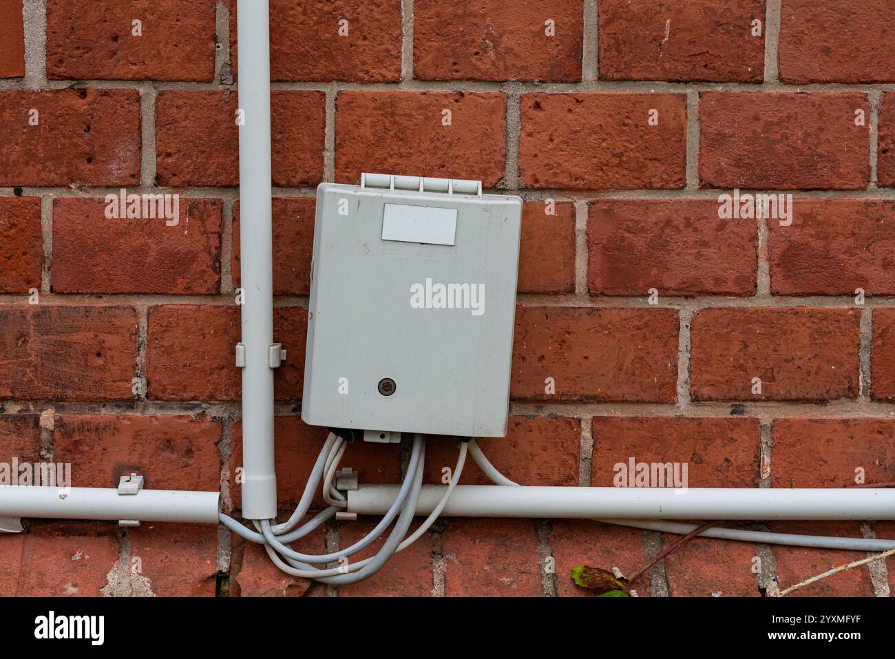 A utility box is securely fastened to a red brick wall, with white ...