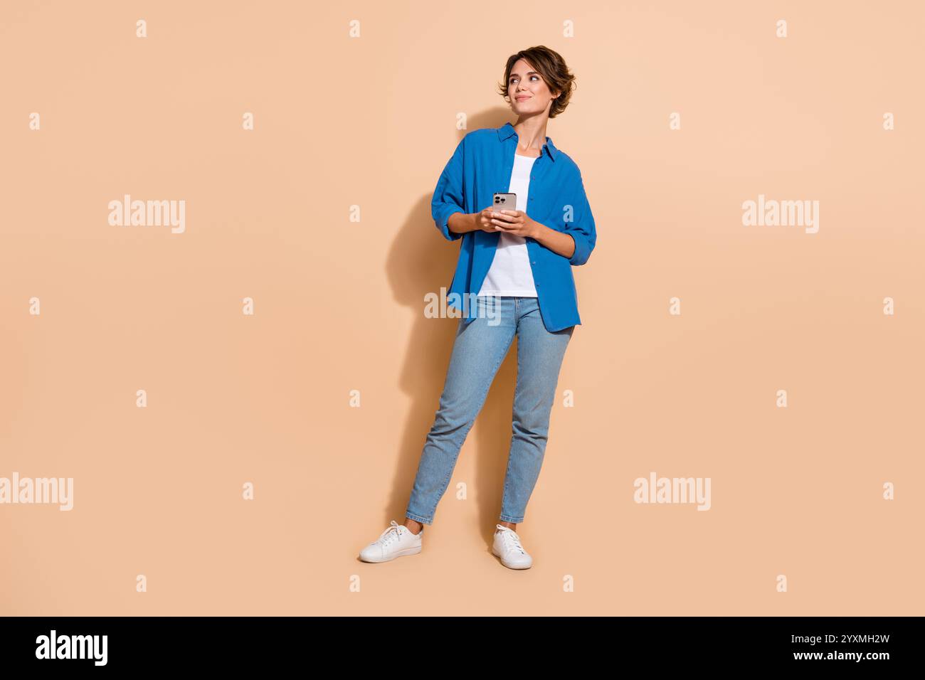 Full length photo of young business lady in blue shirt and jeans using ...