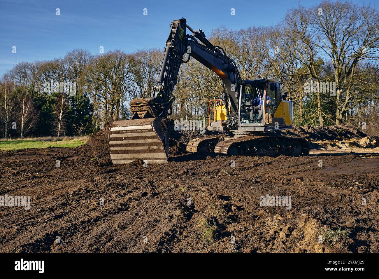 A heavy excavator machine doing work to bring the upper soil in place ...