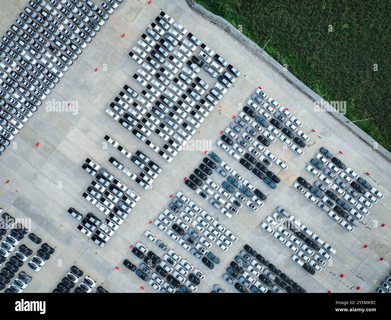 Aerial view of a factory parking lot filled with new cars adjacent to ...