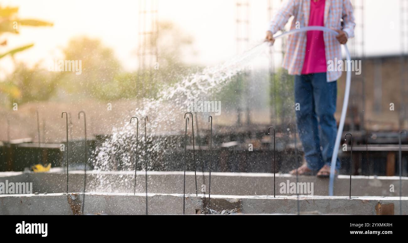 Construction worker watering reinforced concrete beams at a building ...