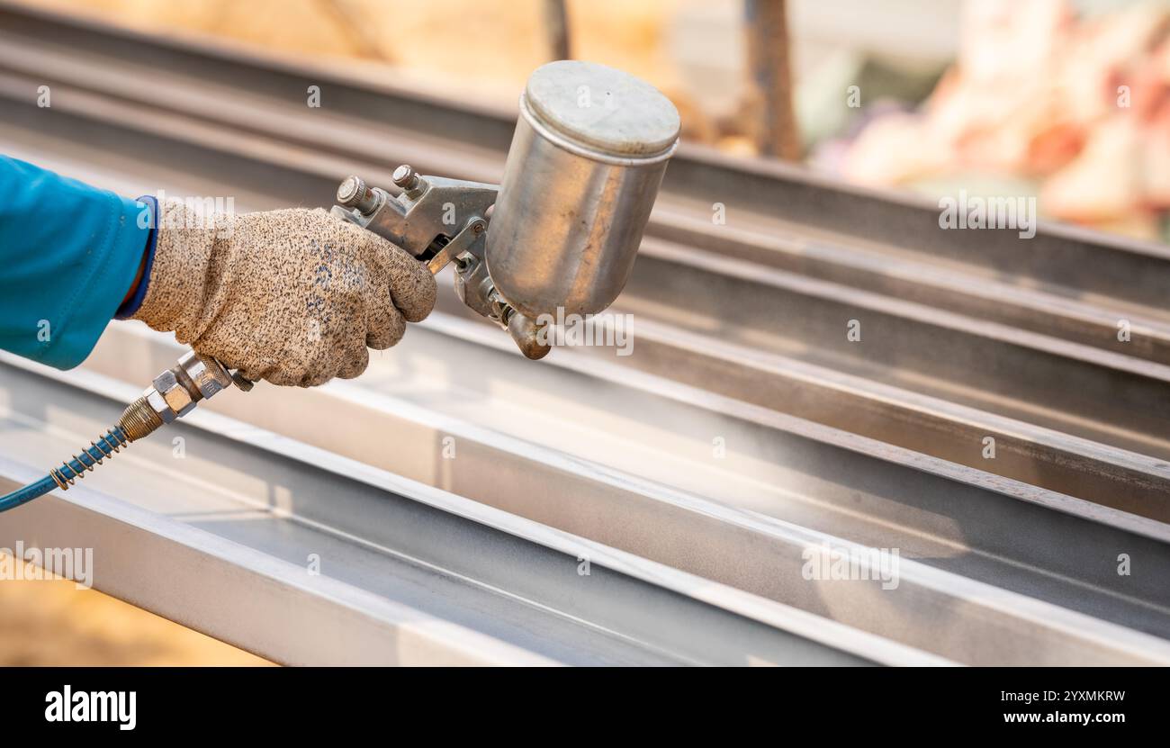 Construction worker painting metal structure surface coating with a ...