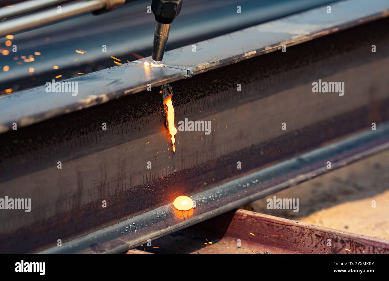 Welder working on metal beam, emitting bright sparks as part of welding ...