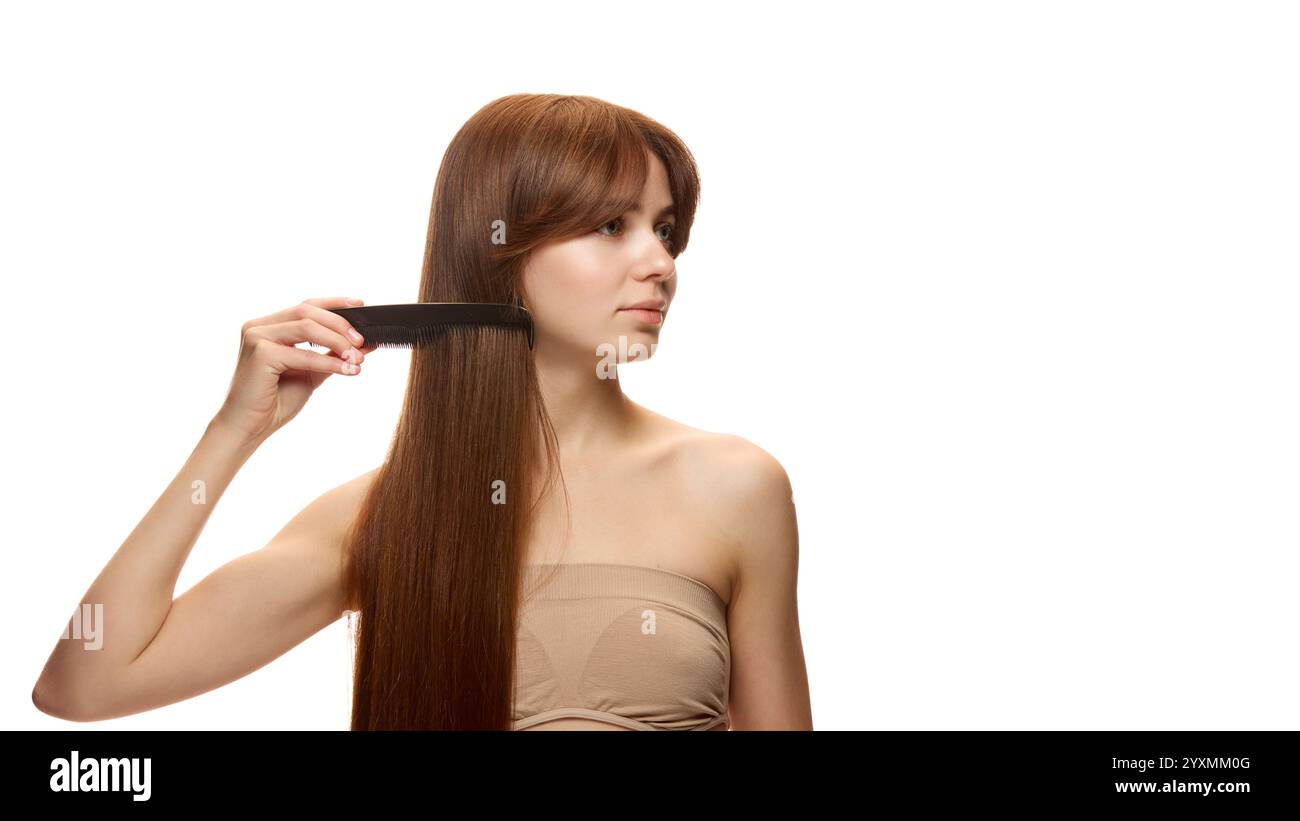 Woman with smooth, shiny, long brown hair gently brushing hair using ...