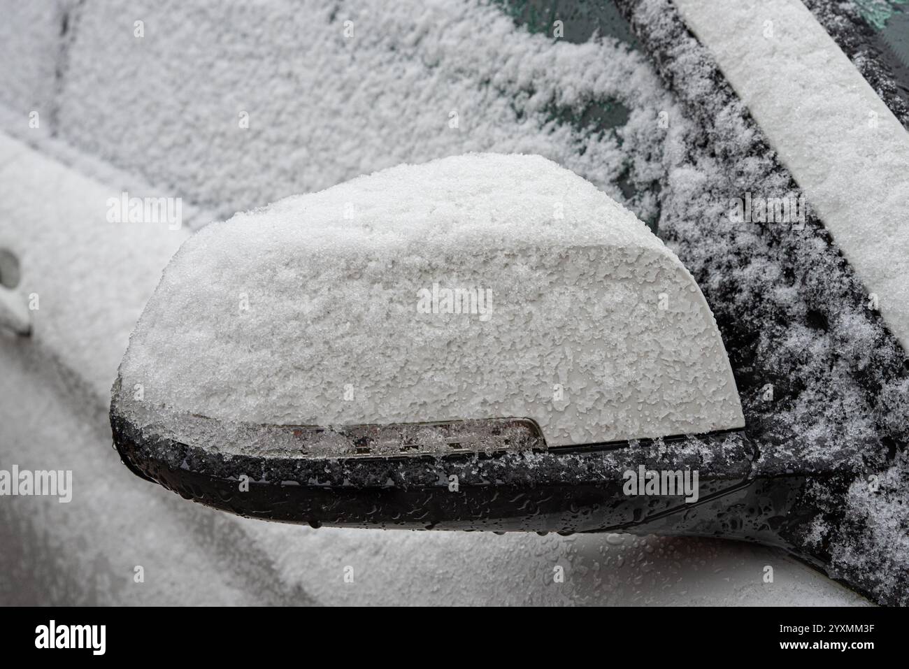 Car side mirror and window covered in snow and ice. Cold winter weather ...