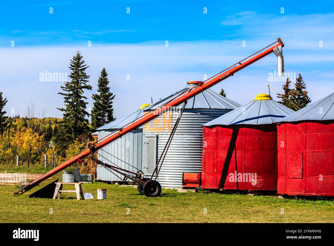 A red silo with a silver crane attached to it. The silo is next to a ...
