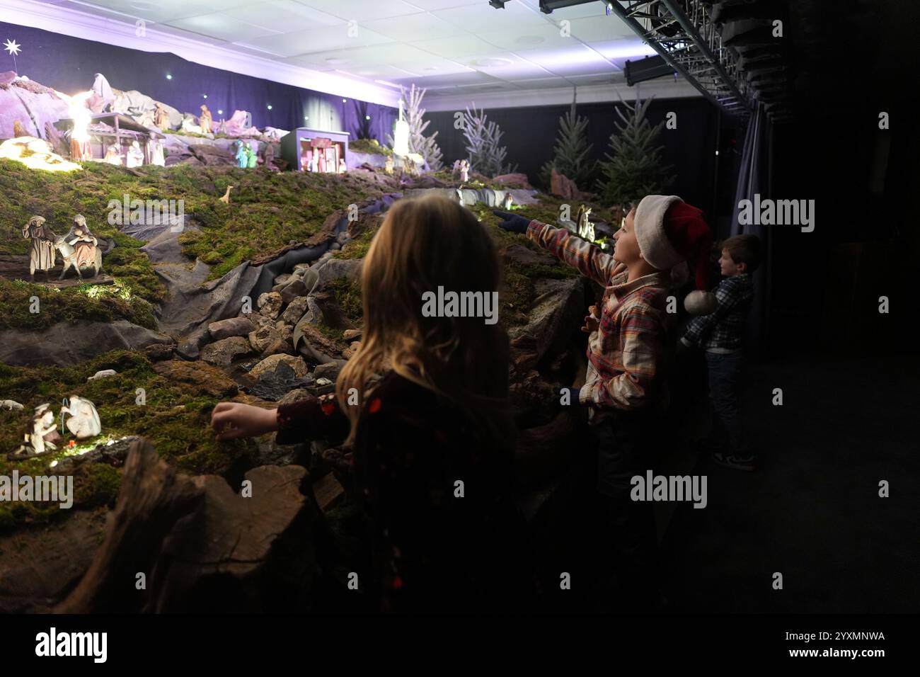 A boy points to miniature wooden figurines that are part of a Nativity ...