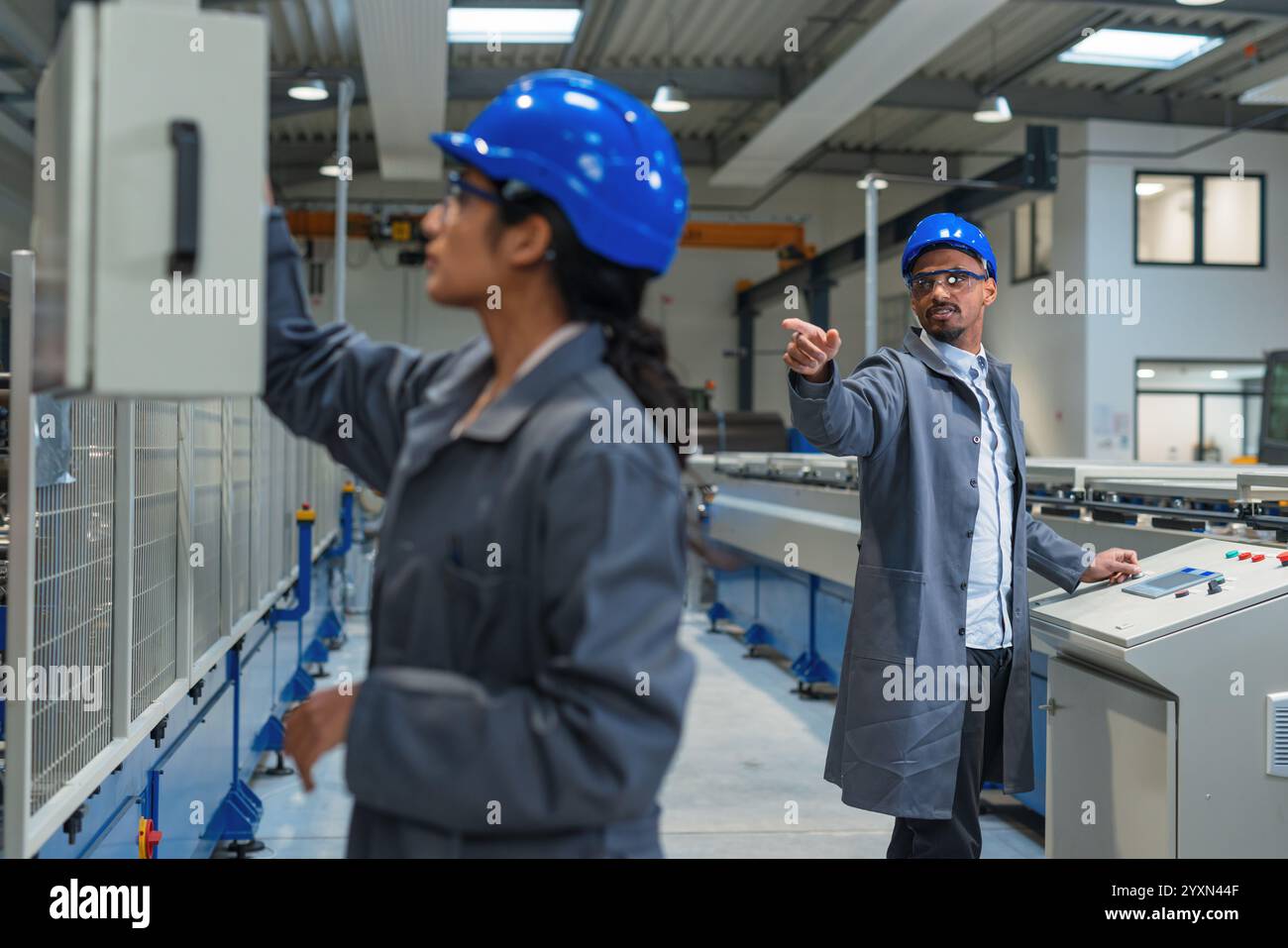 Two engineers, an Indian woman, and African American man, supervising ...