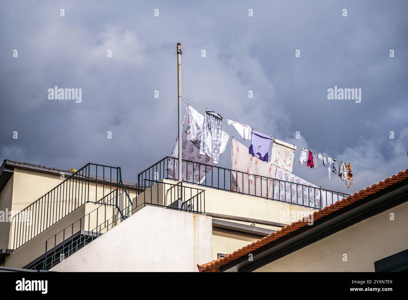 Clothes and linens drying outdoors on a rooftop clothesline beneath ...