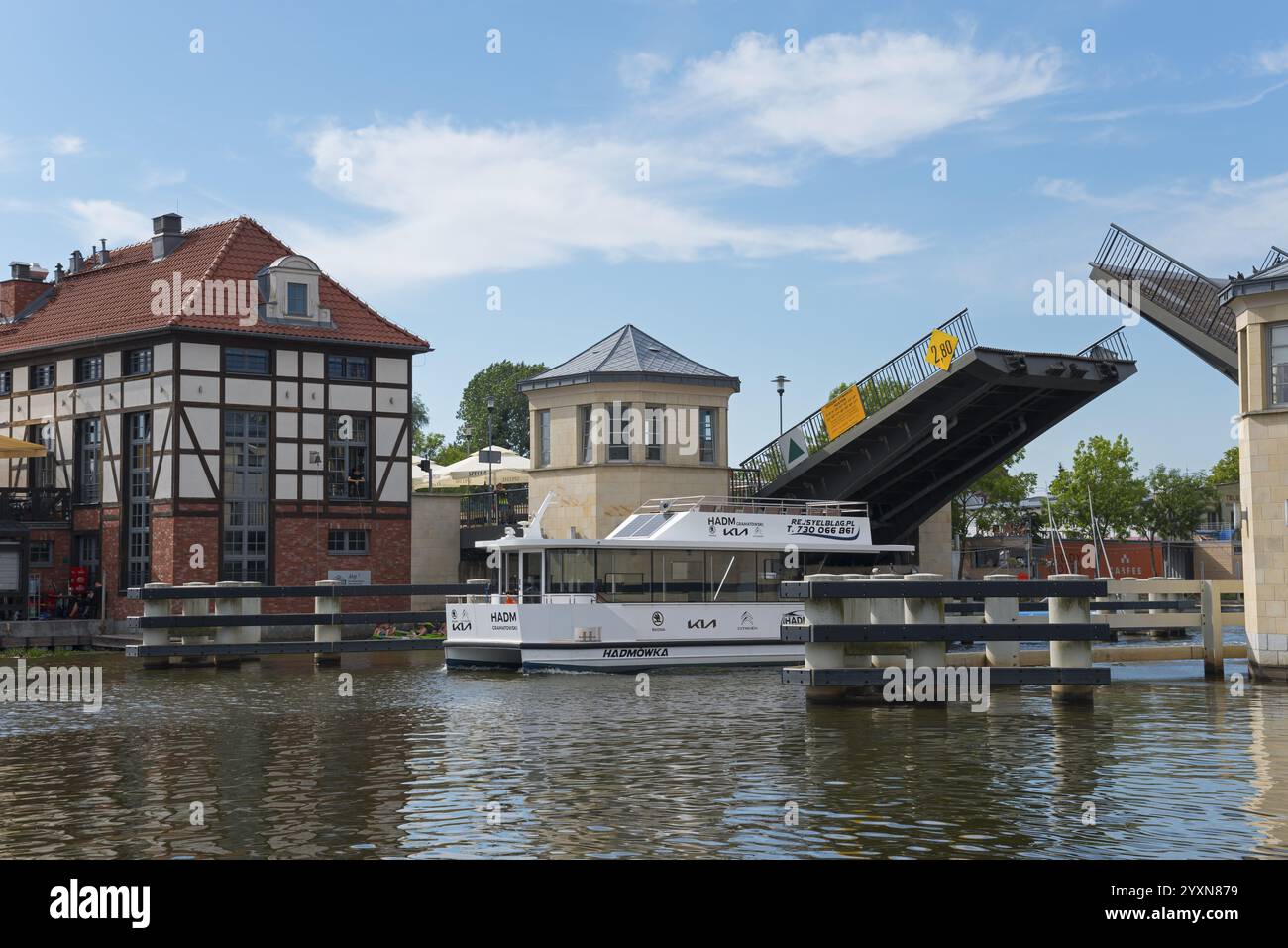 A modern boat under a raised bascule bridge in front of half-timbered ...