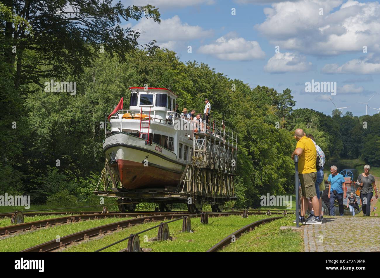 A boat being transported overland on a railway wagon, watched by a ...