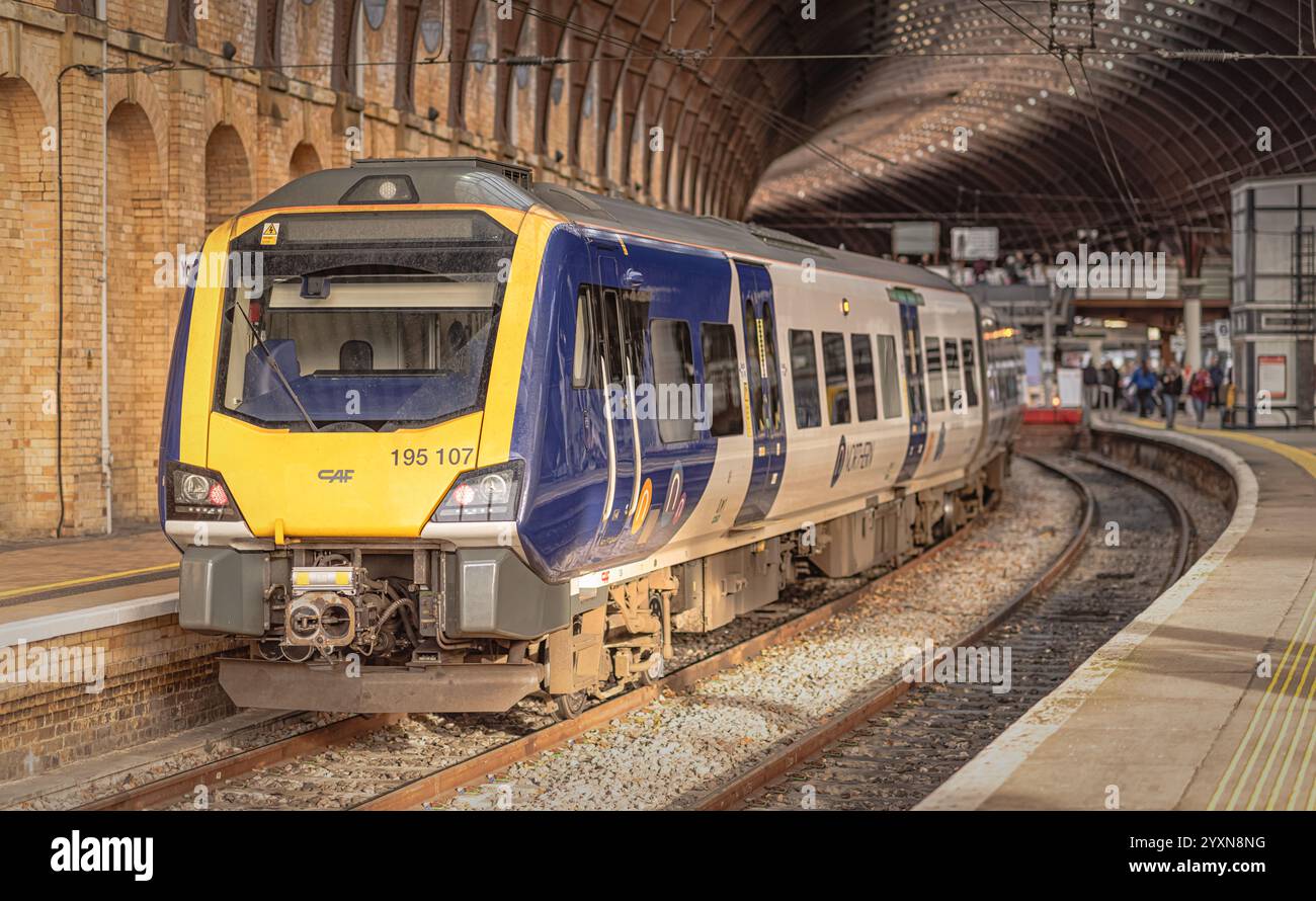 A railway train locomotive stands at a station platform curving inwards ...