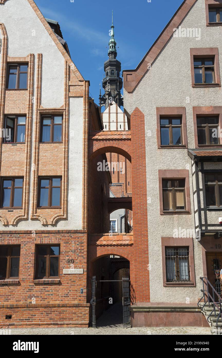 A narrow passageway between two historic brick buildings with a tower ...