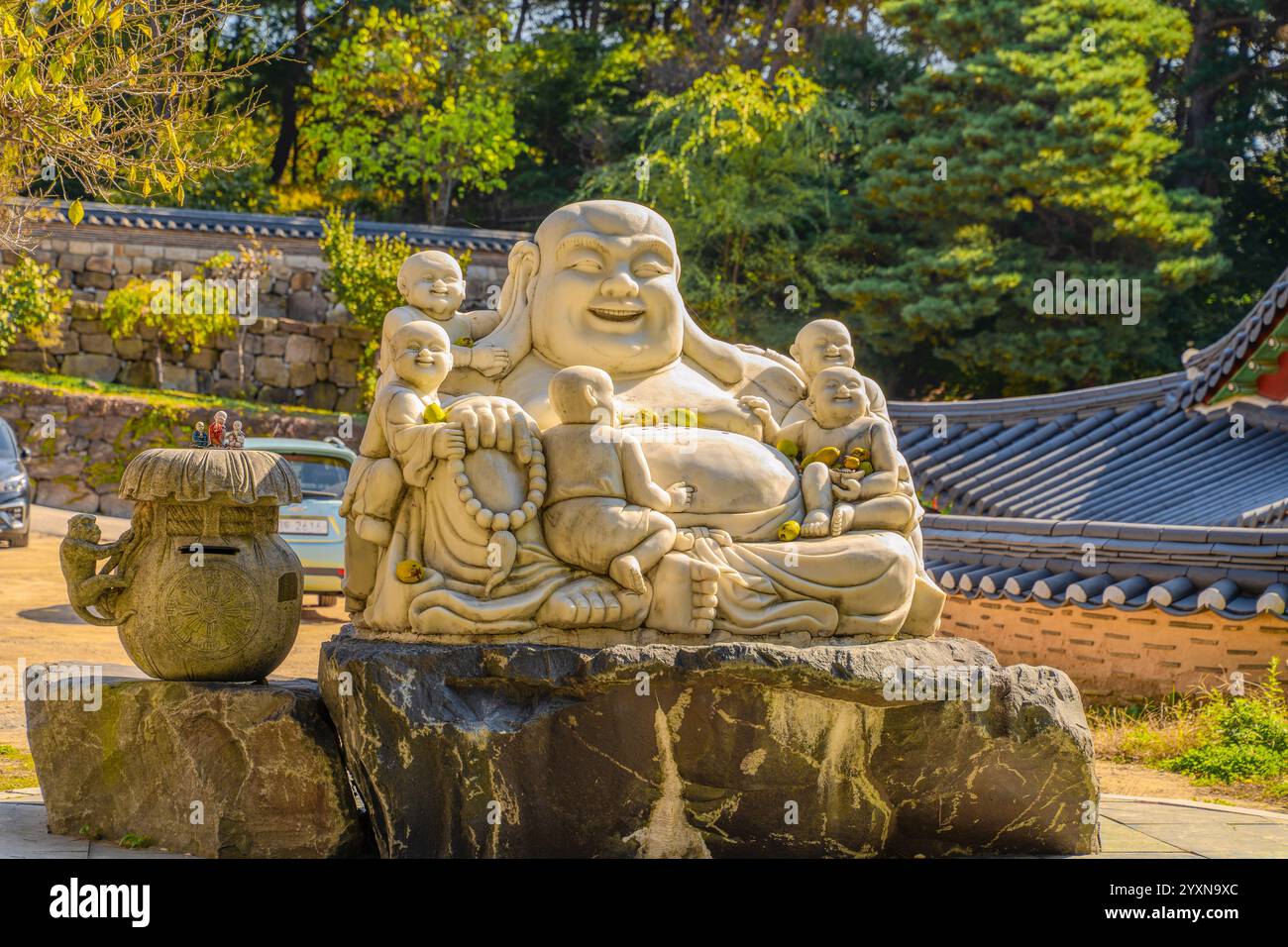 A stone statue of a plump and benevolent Buddhist monk with a young ...