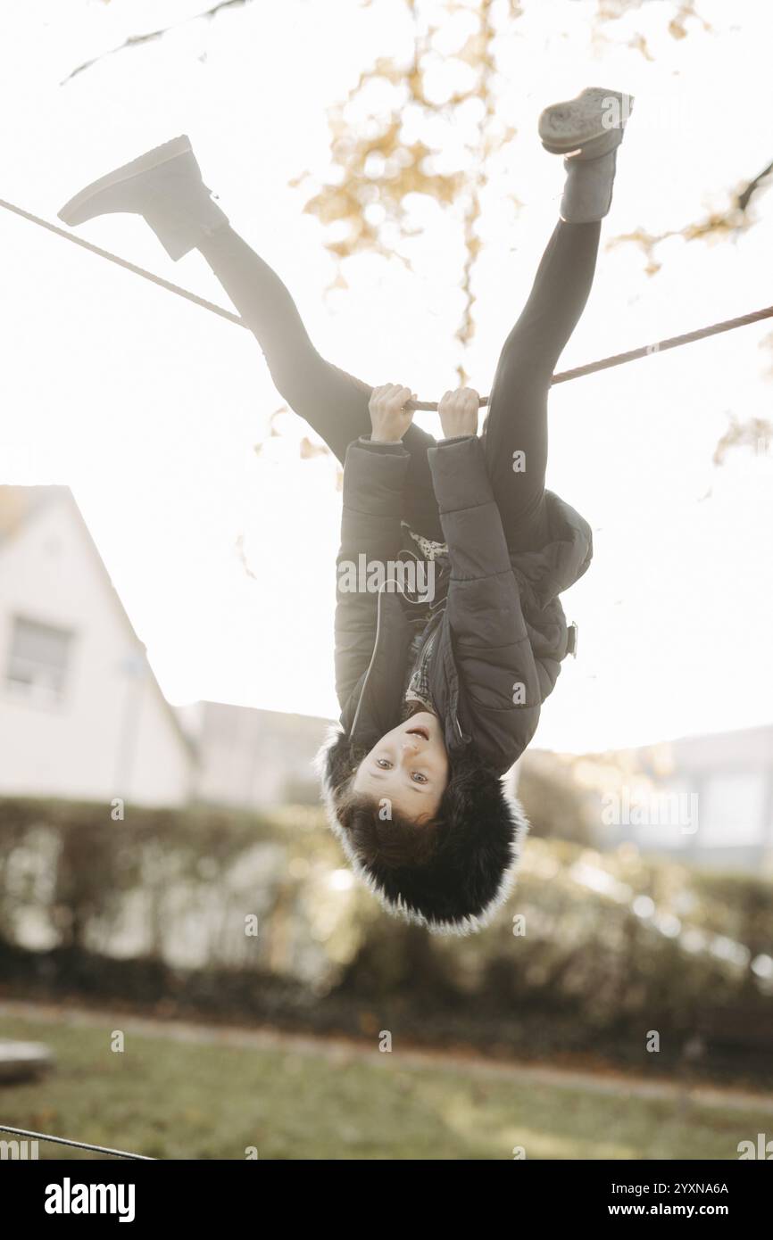 Girl hanging upside down on a gym rope at the playground Stock Photo - Alamy
