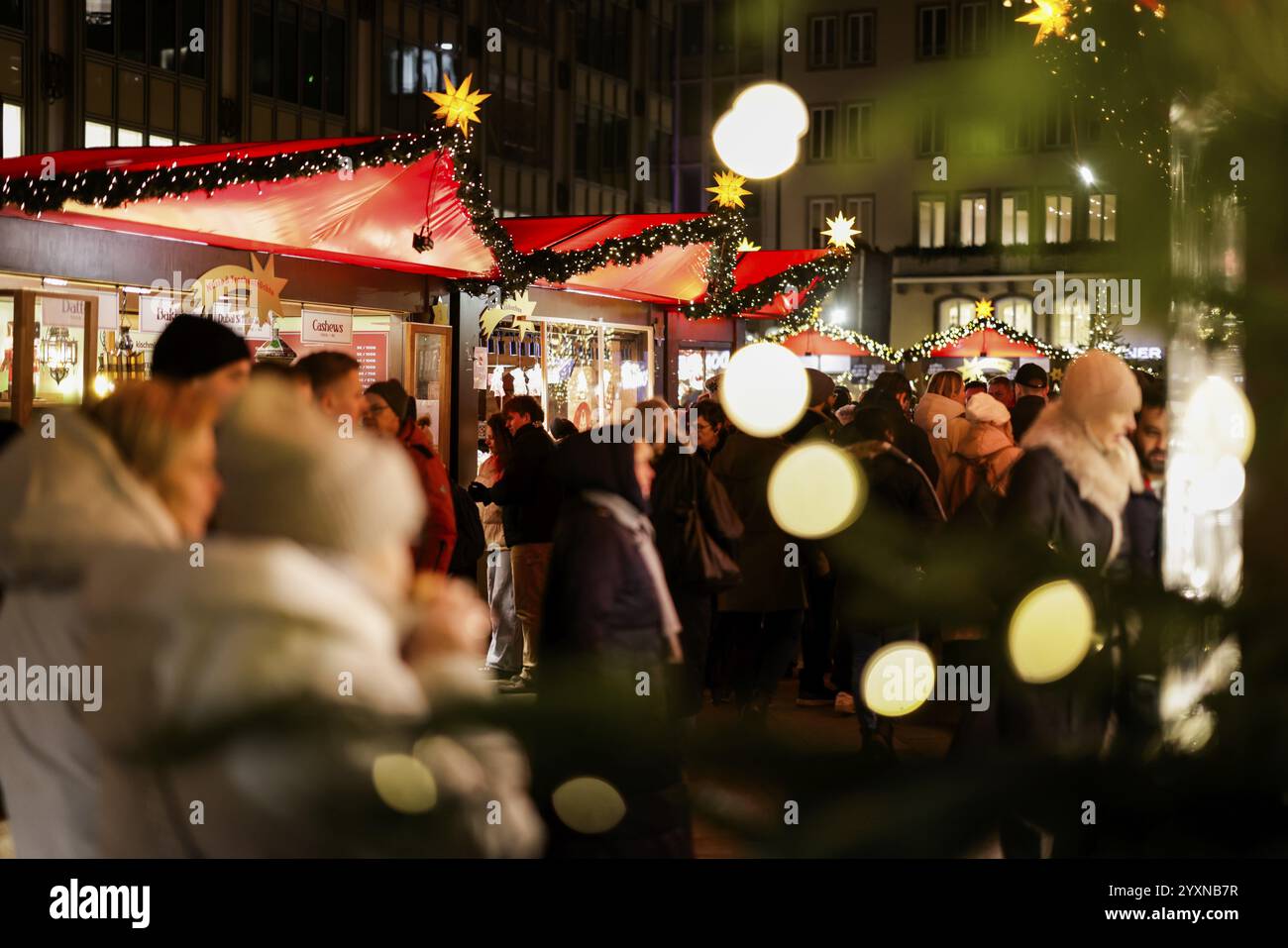 Large crowds of people at a brightly lit Christmas market at night ...
