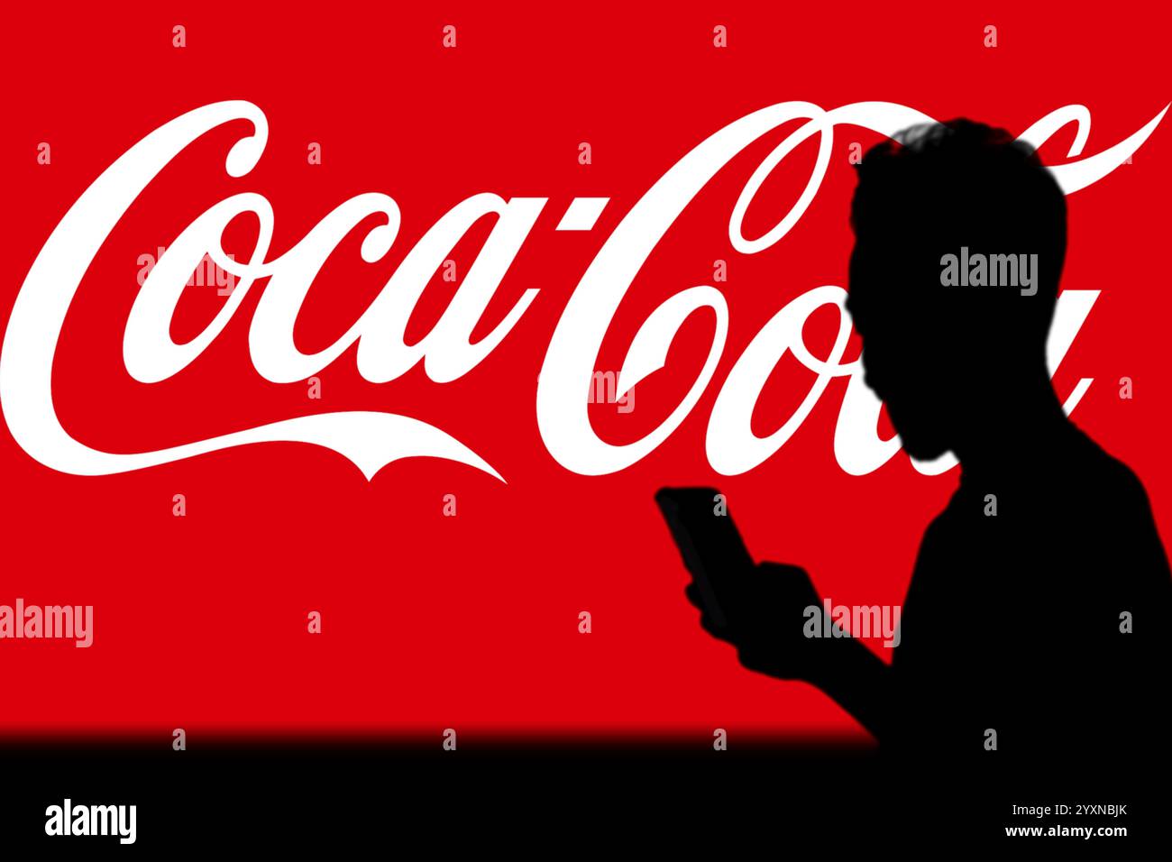 Coca-Cola logo is seen on a mobile phone and a computer screen Stock ...