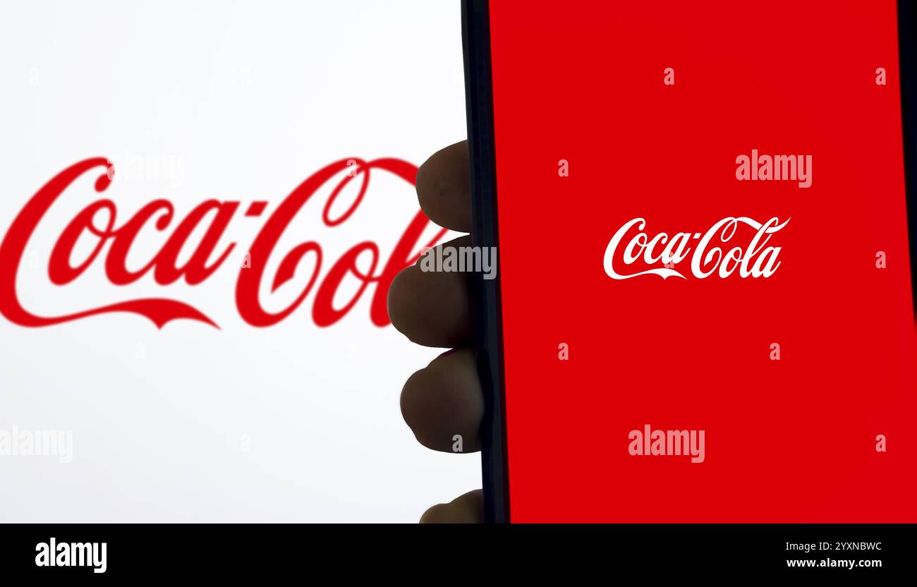 Coca-Cola logo is seen on a mobile phone and a computer screen Stock ...