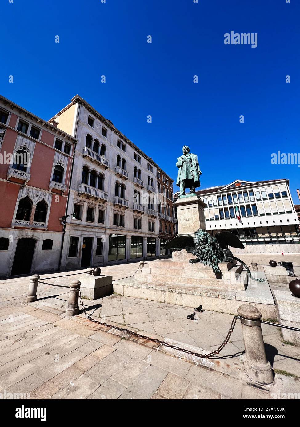 A striking historic statue stands in a Venetian square with traditional ...
